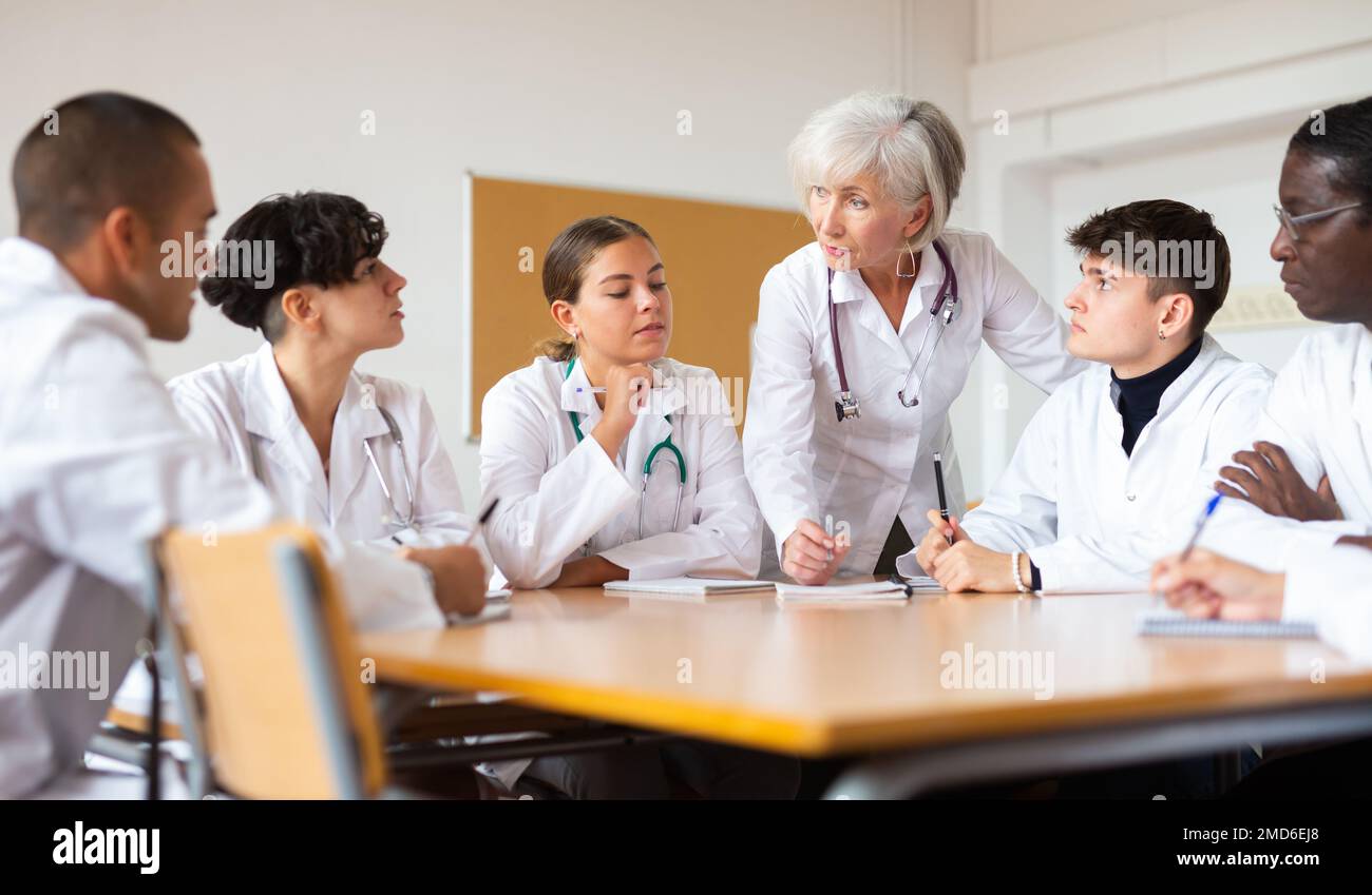 Group of medical students in white coats studying in classroom Stock ...