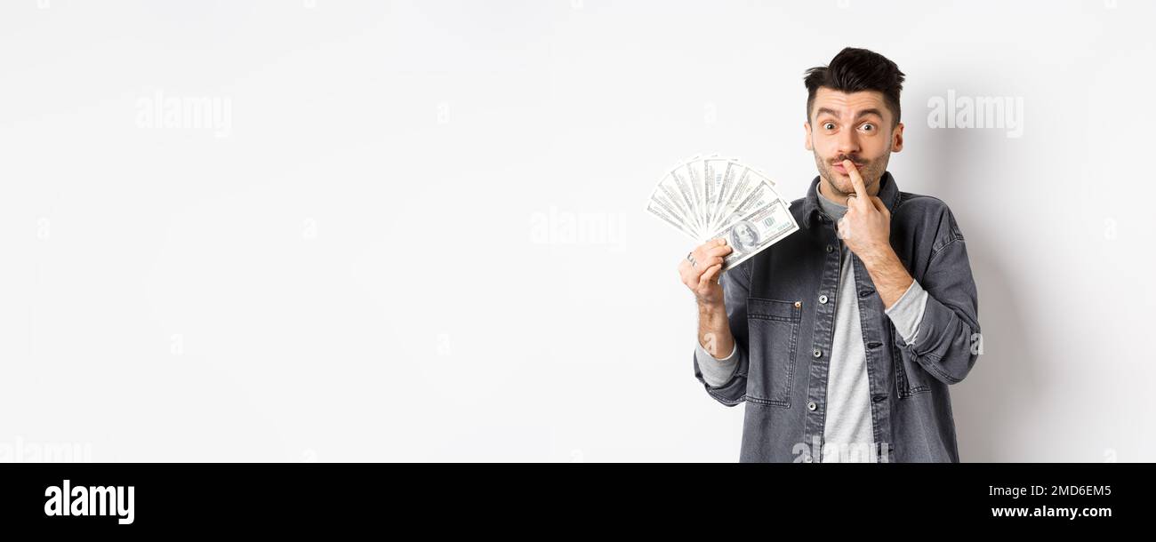 Pensive guy holding money and thinking what buy, pondering about ...