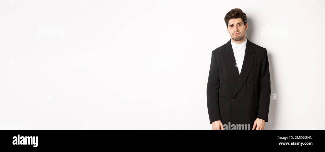 Image of gloomy and sad handsome male model in black suit, frowning and ...