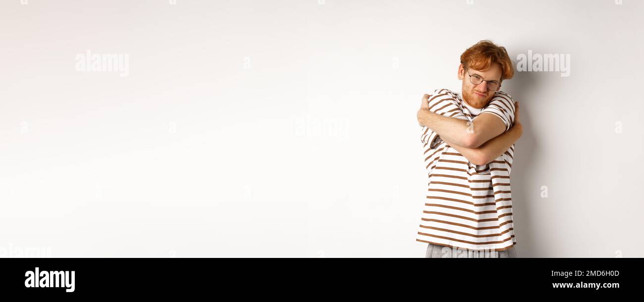 Reluctant young man with messy red hair unwilling do something, hugging ...