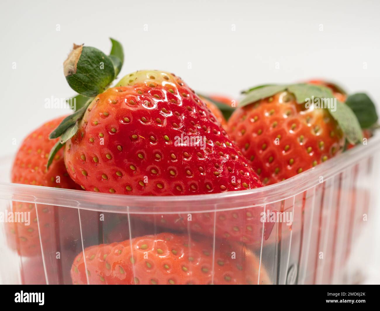 Ripe strawberries in a plastic package on a white background ...