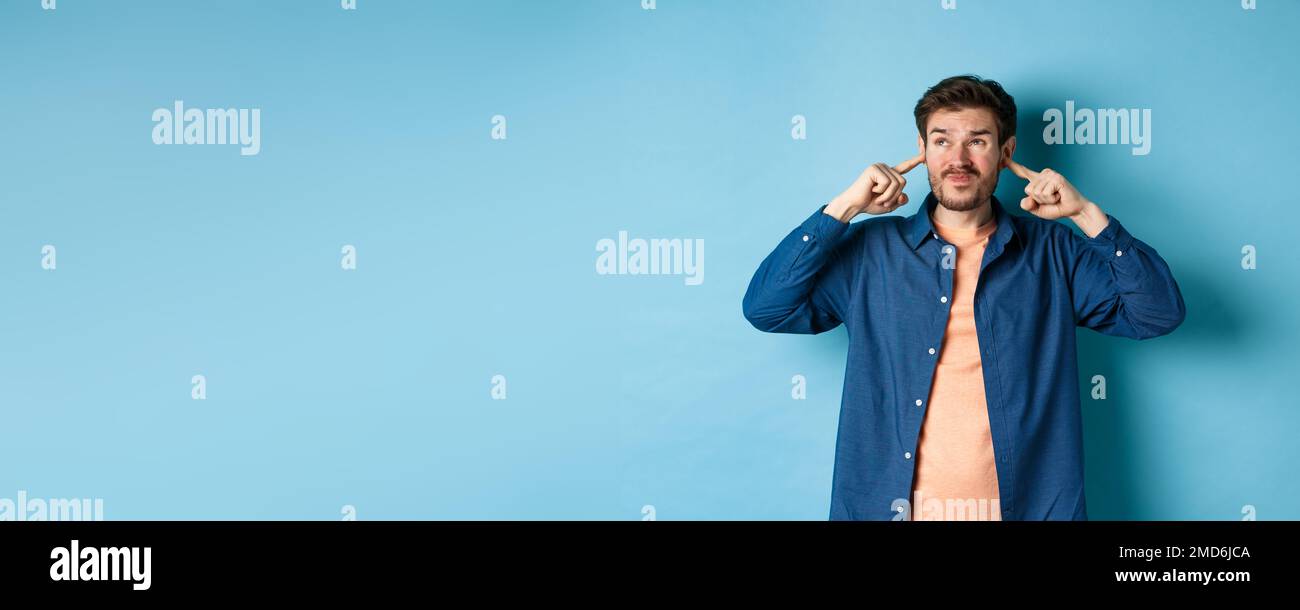 Annoyed young man block sound, shut ears with fingers and grimacing ...