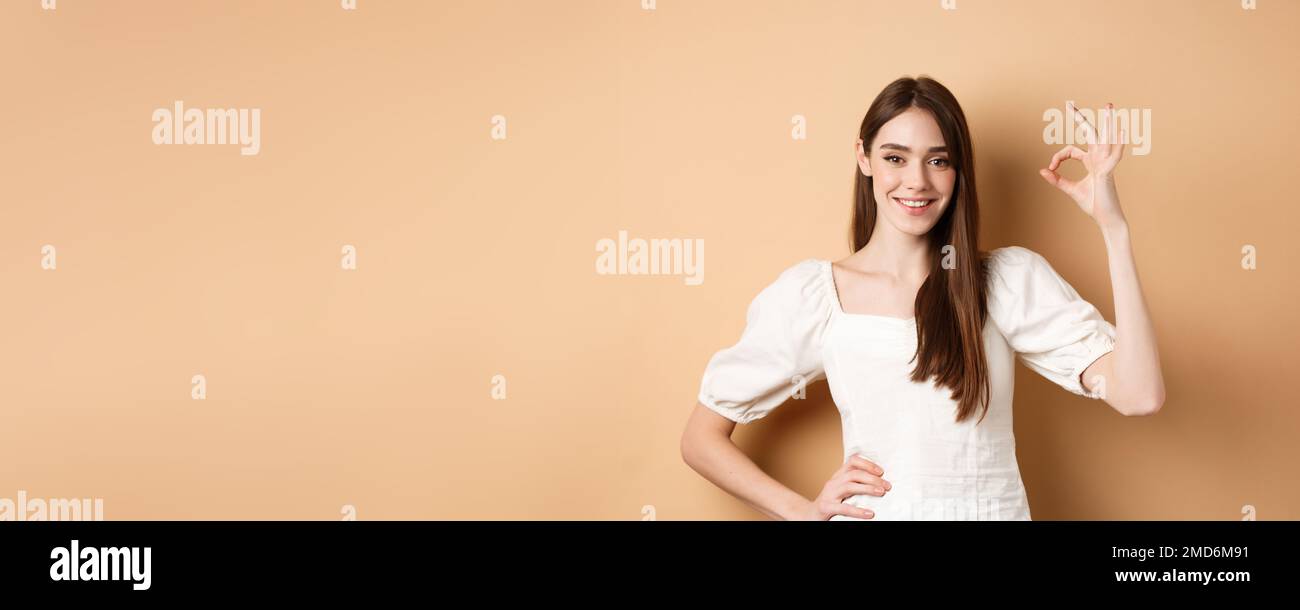 Very good. Smiling cute woman in white blouse showing okay sign in ...