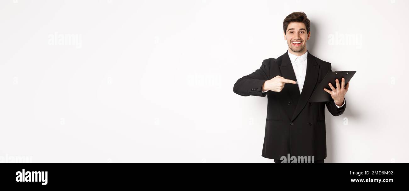 Image of handsome smiling businessman in black suit, pointing finger at ...