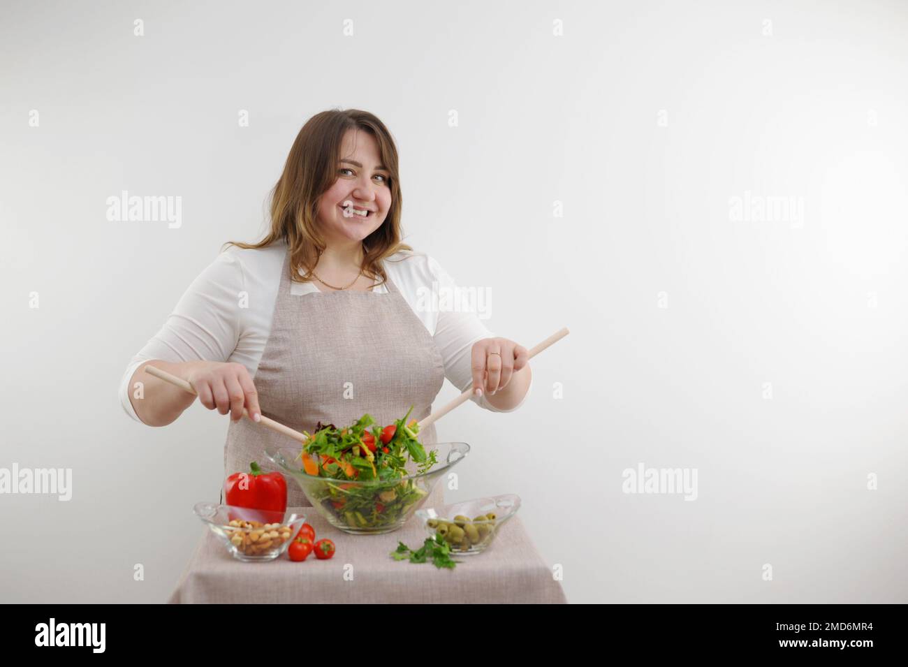 successful promotional photo of beautiful curvy woman preparing salad ...