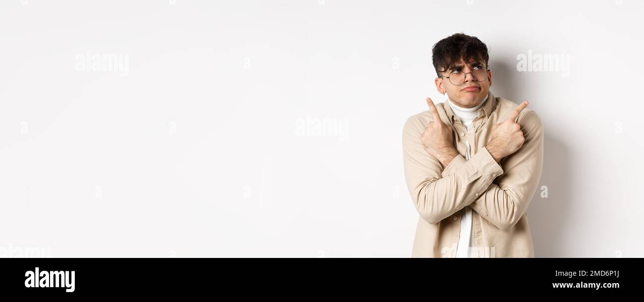 Indecisive funny young man having troubles with making choice, pointing ...