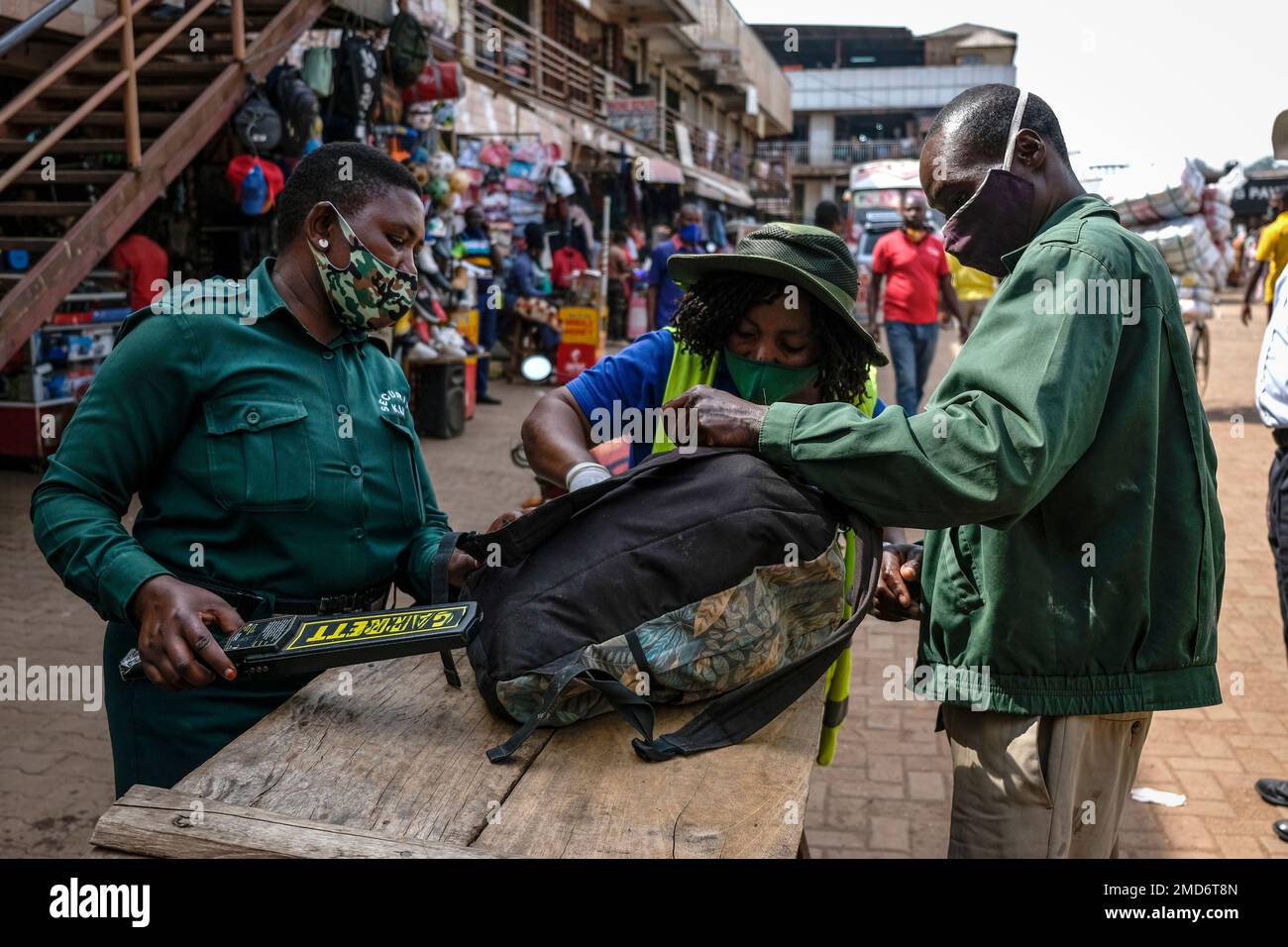 A bus security officer checks a passenger's backpack using a metal ...