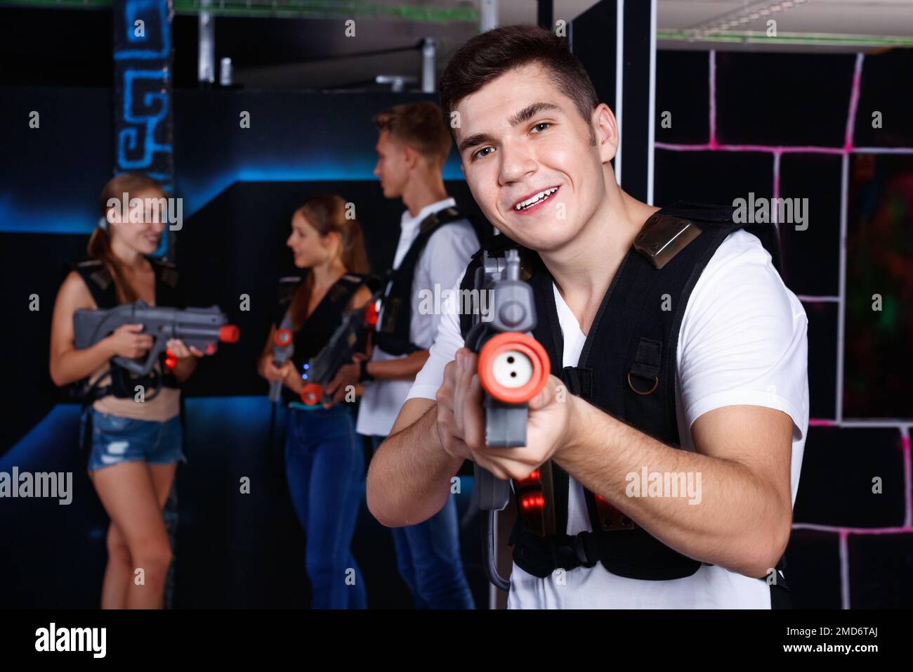 Portrait of excited guy with laser pistol playing laser tag in arena ...