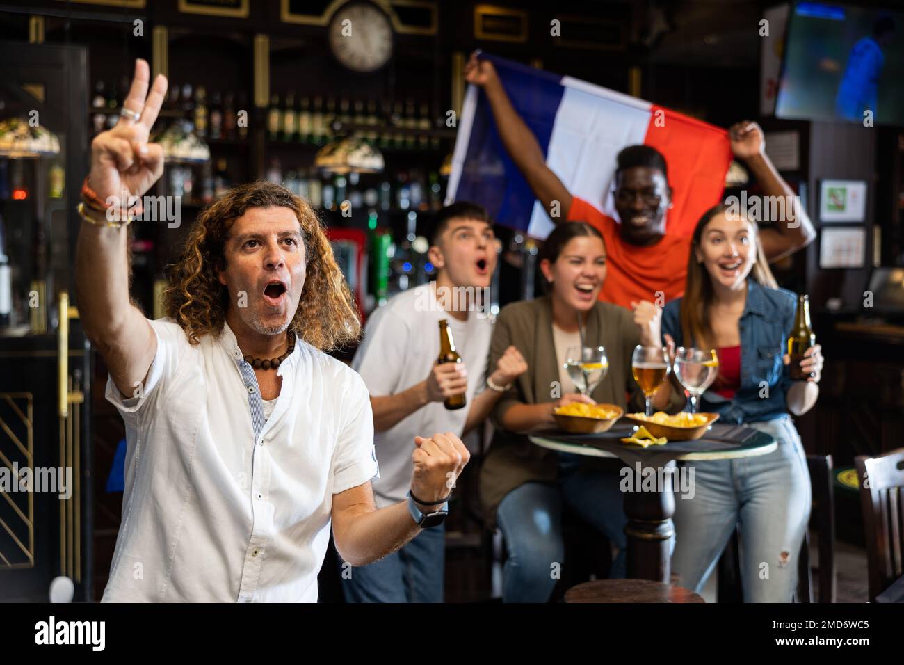 Expressive French man cheering for favorite football team in sports bar ...