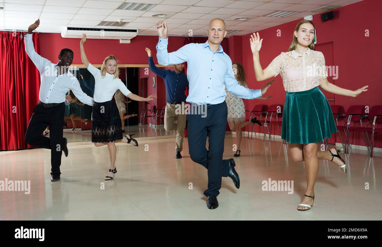 Young positive people dancing twist together at modern dance studio ...