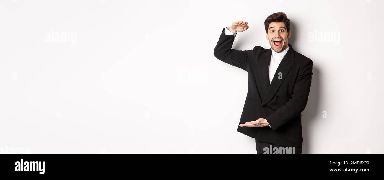 Portrait of excited handsome man in suit, shaping big object on copy ...
