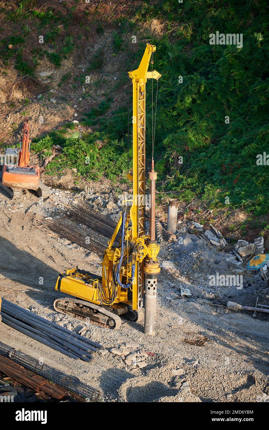 The yellow pile driver drives the foundation piles at the construction ...
