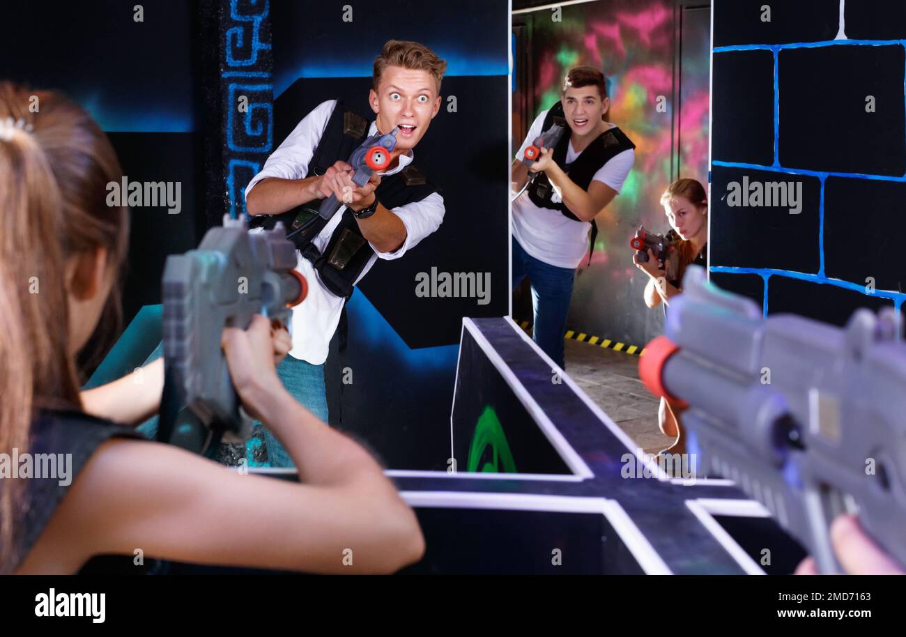 Two laser tag teams playing enthusiastically and aiming at each other ...