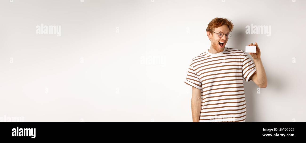 Shopping and finance concept. Excited young man with red hair, staring ...