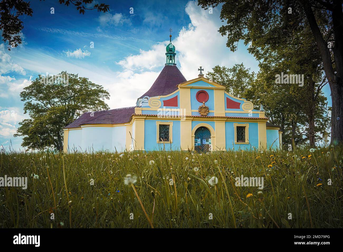 The exterior of a small church in a beautiful garden under blue cloudy ...