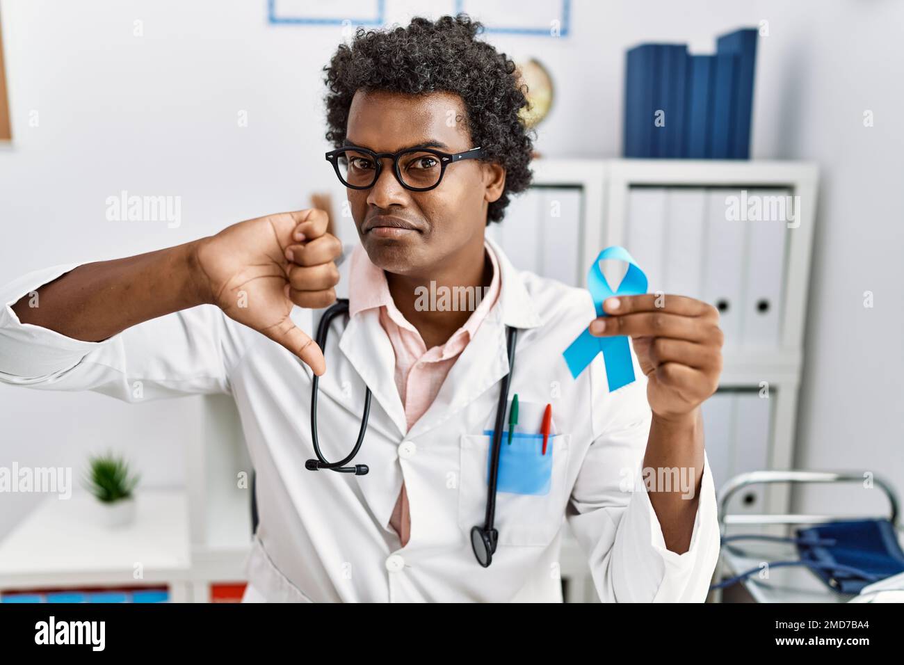 African doctor man holding blue ribbon with angry face, negative sign ...