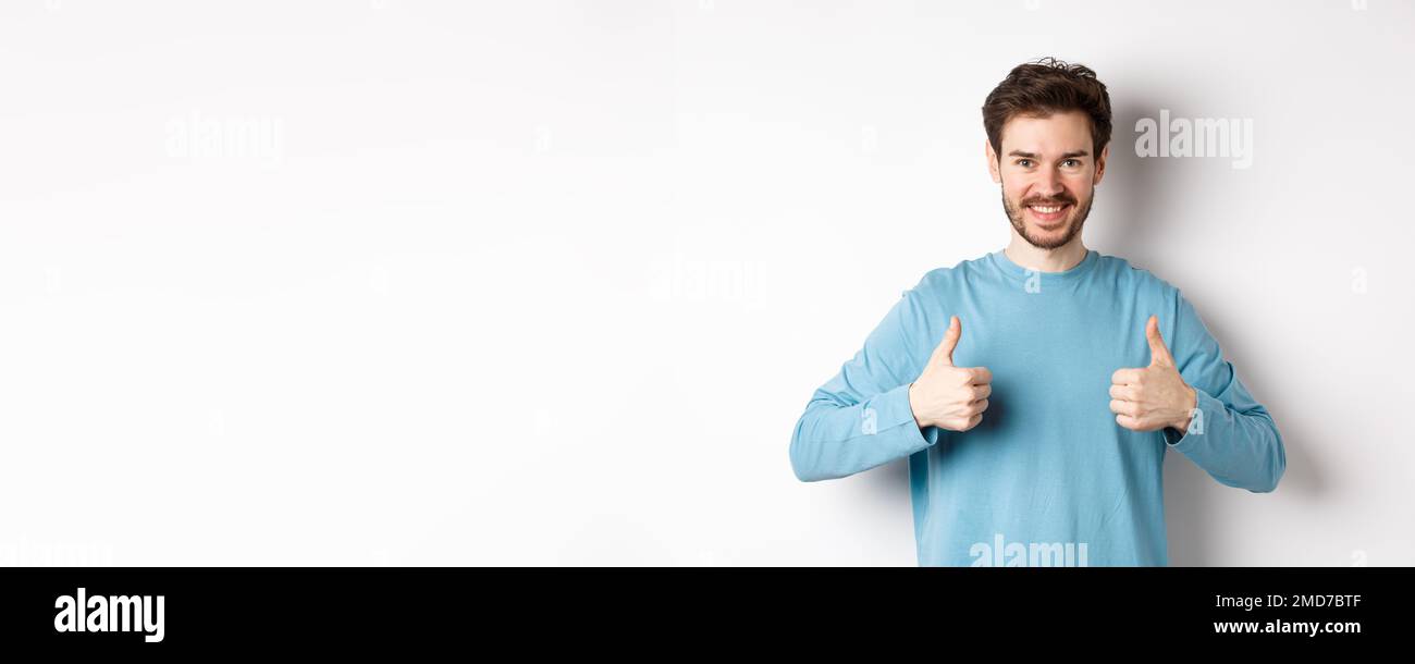 Smiling handsome man showing thumbs up, like and approve good choice ...
