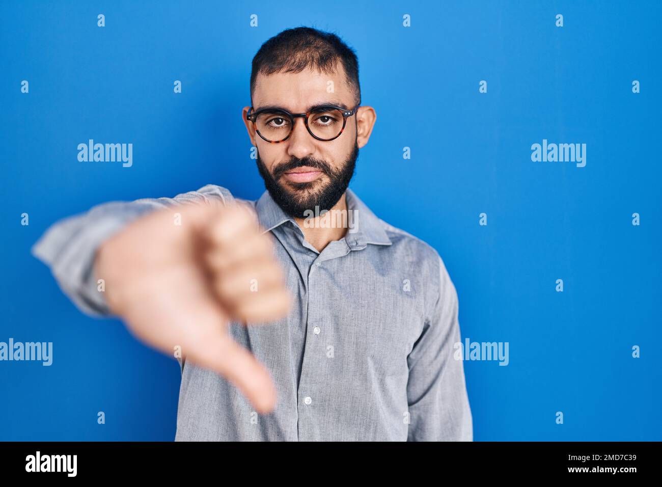 Middle east man with beard standing over blue background looking ...