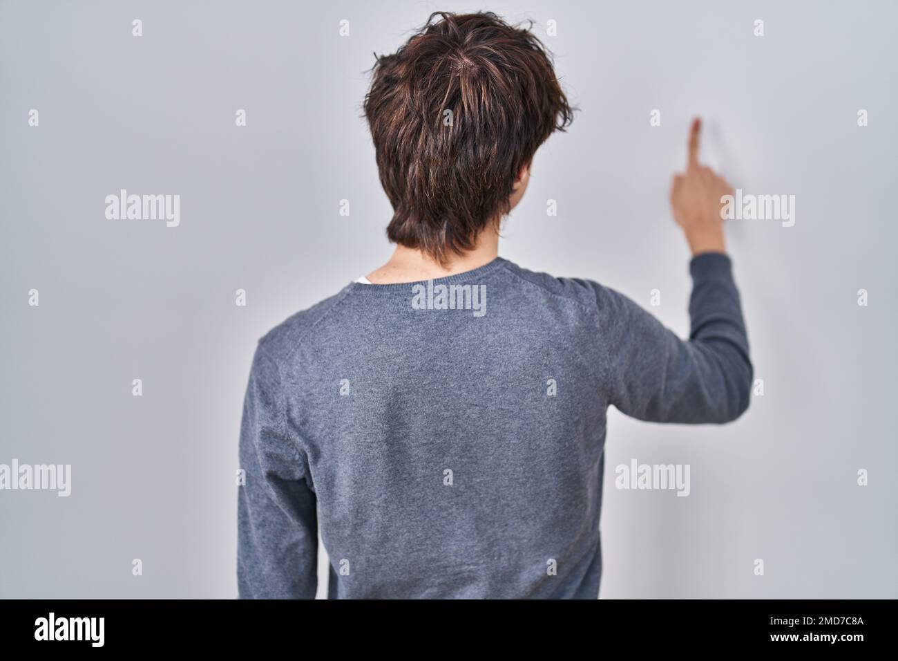 Young man standing over isolated background posing backwards pointing ...
