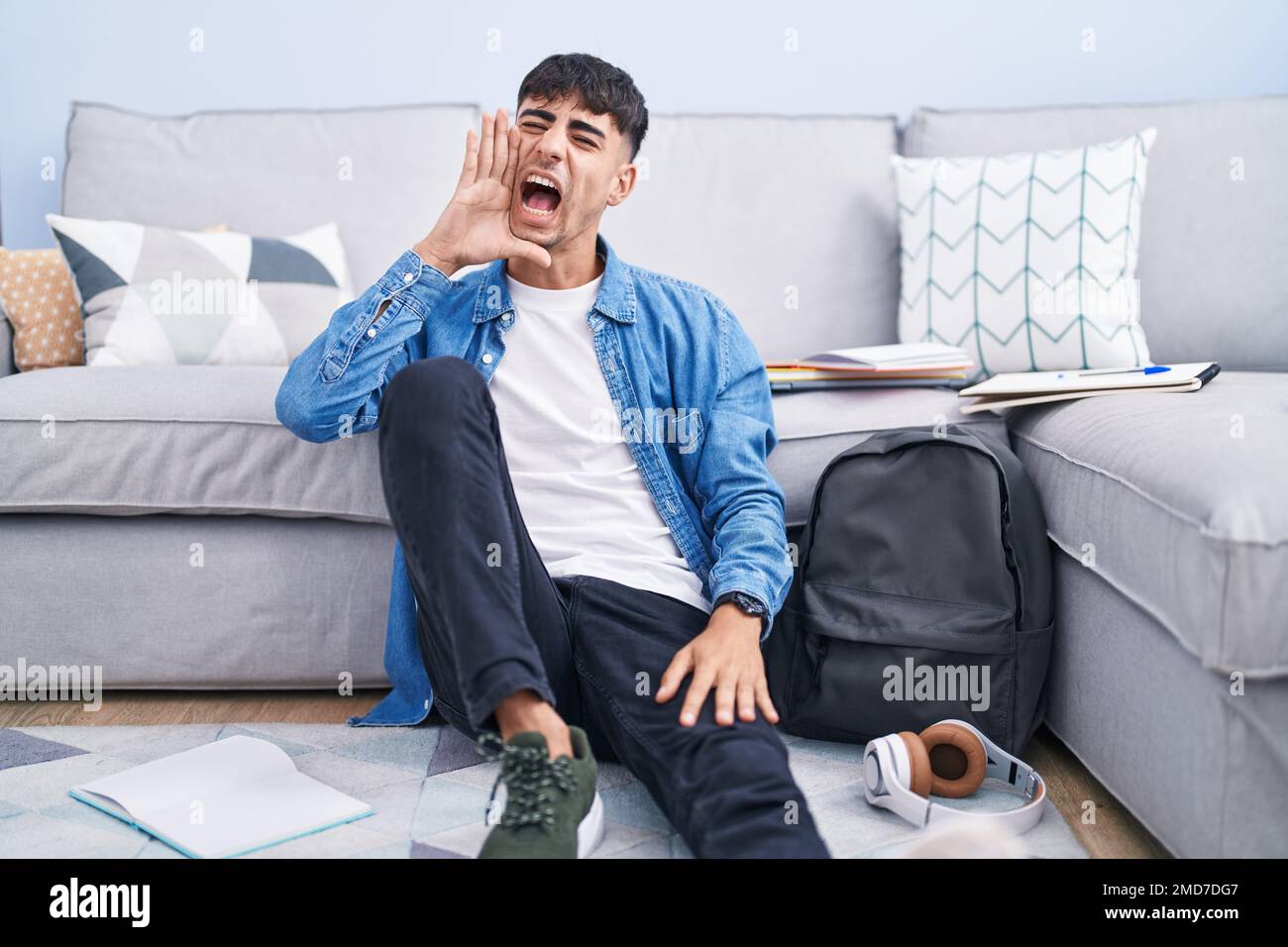 Young hispanic man sitting on the floor studying for university ...