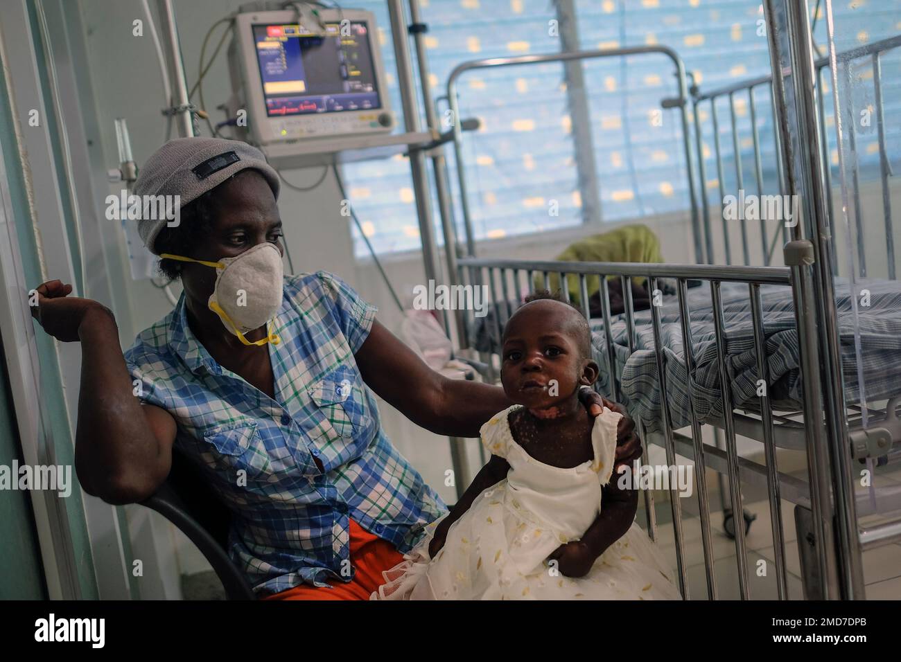 A COVID-19 patient rests on her mother's leg at the Saint Damien ...