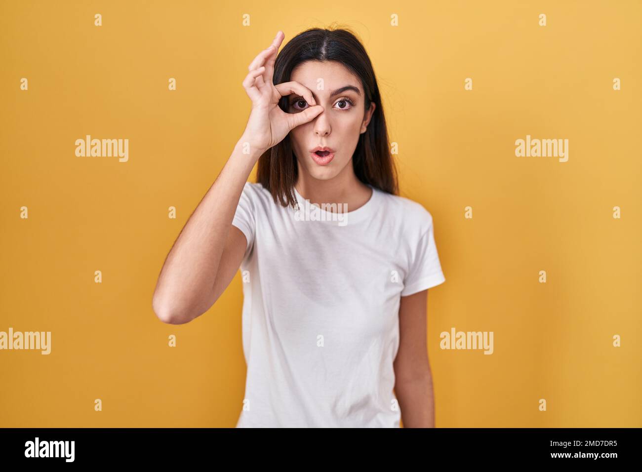 Young beautiful woman standing over yellow background doing ok gesture ...