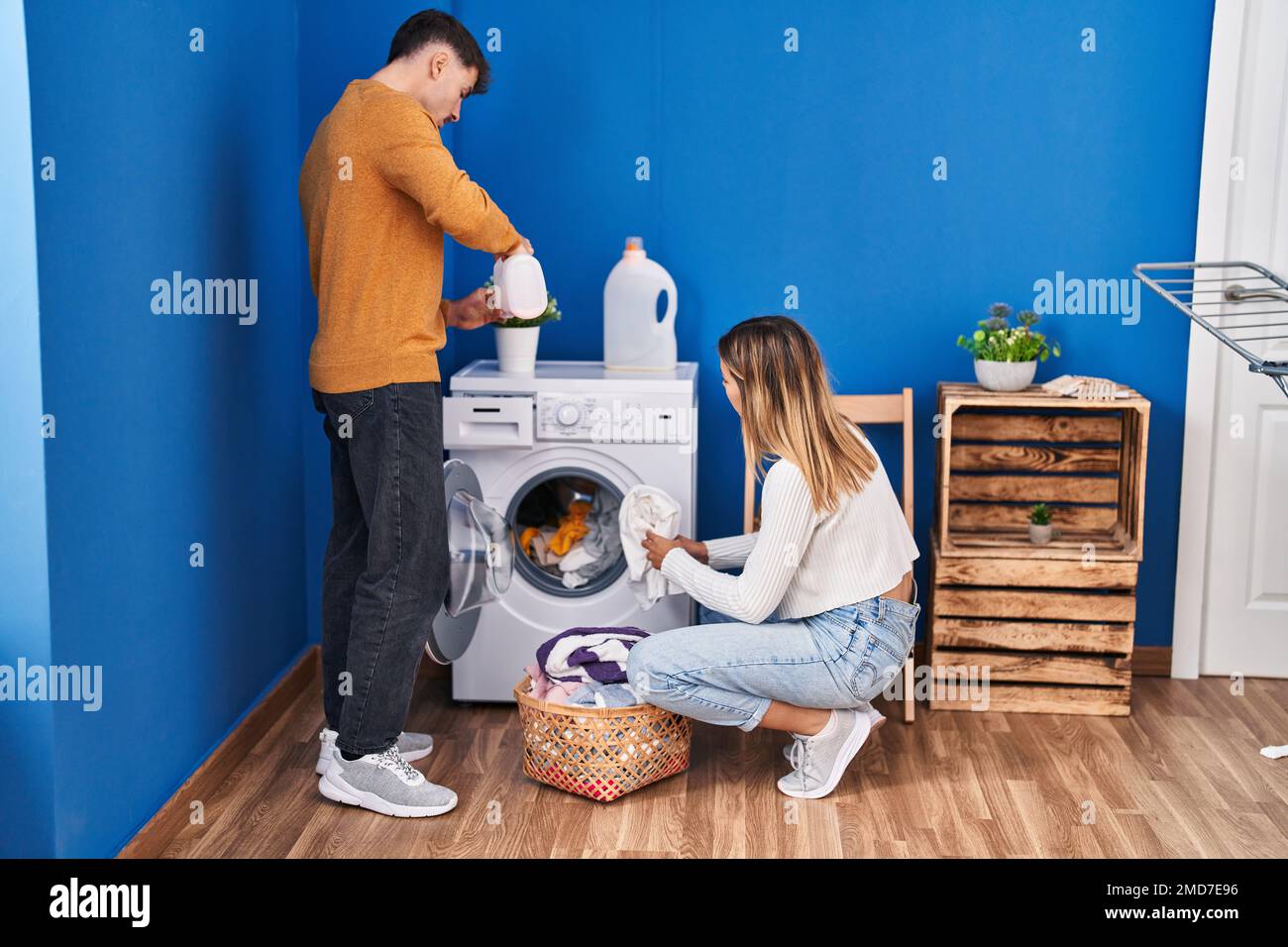 Young man and woman couple washing clothes sitting on floor at laundry room Stock Photo - Alamy