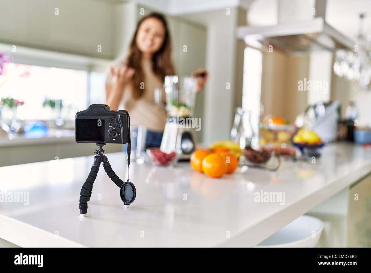 Young beautiful hispanic woman preparing vegetable smoothie with ...