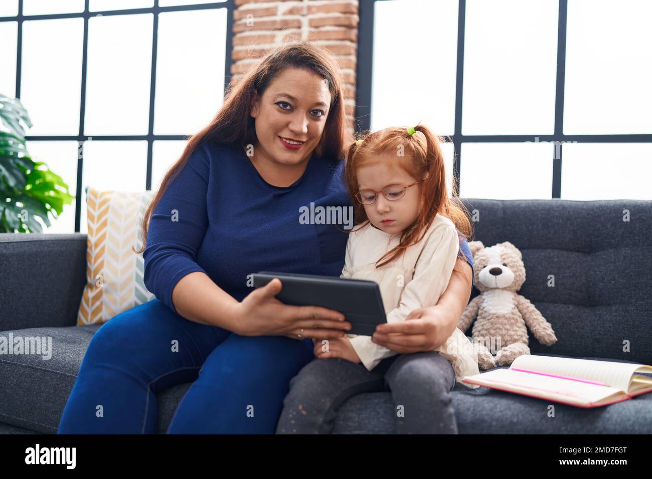 Teacher and student using touchpad sitting on sofa at home Stock Photo ...