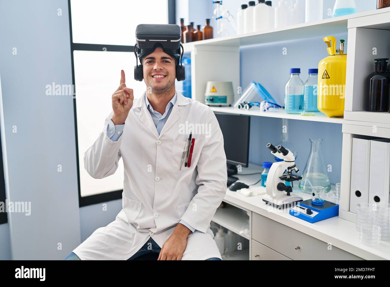 Young hispanic man working at scientist laboratory wearing vr glasses ...