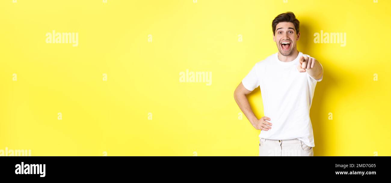 Happy guy pointing finger at camera and laughing, check out something ...