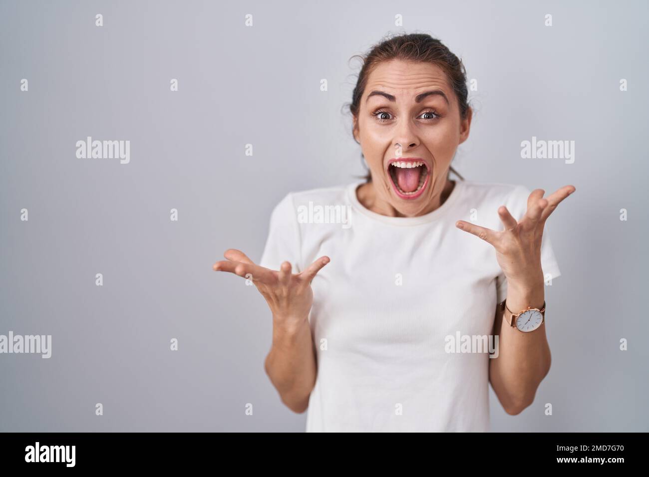 Beautiful brunette woman standing over isolated background celebrating ...