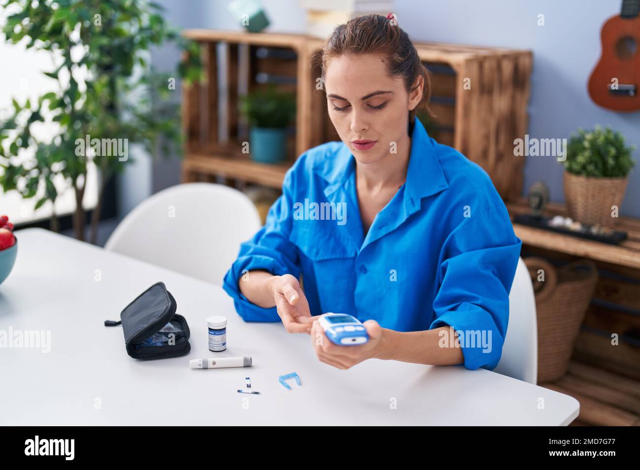 Young woman measuring glucose using glucometer at home Stock Photo - Alamy