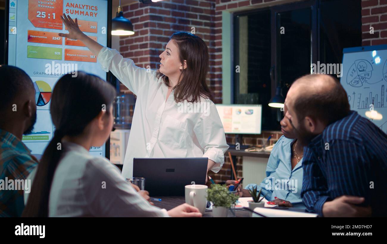 Employee speaking in business meeting presentation, holding laptop, financial analytics report ...