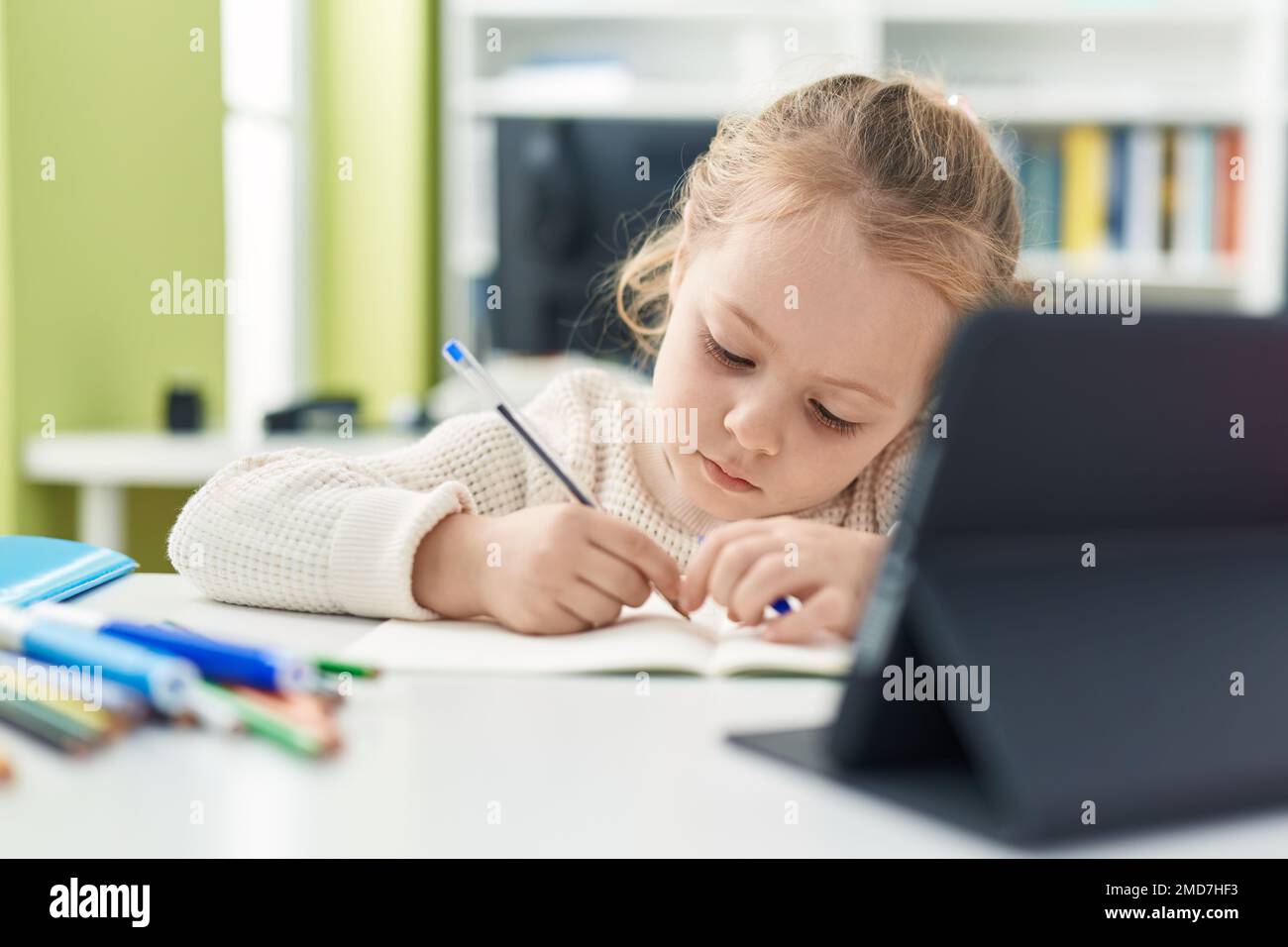 Adorable blonde girl student using touchpad writing on notebook at ... Adorable blonde girl student using touchpad writing on notebook at ...