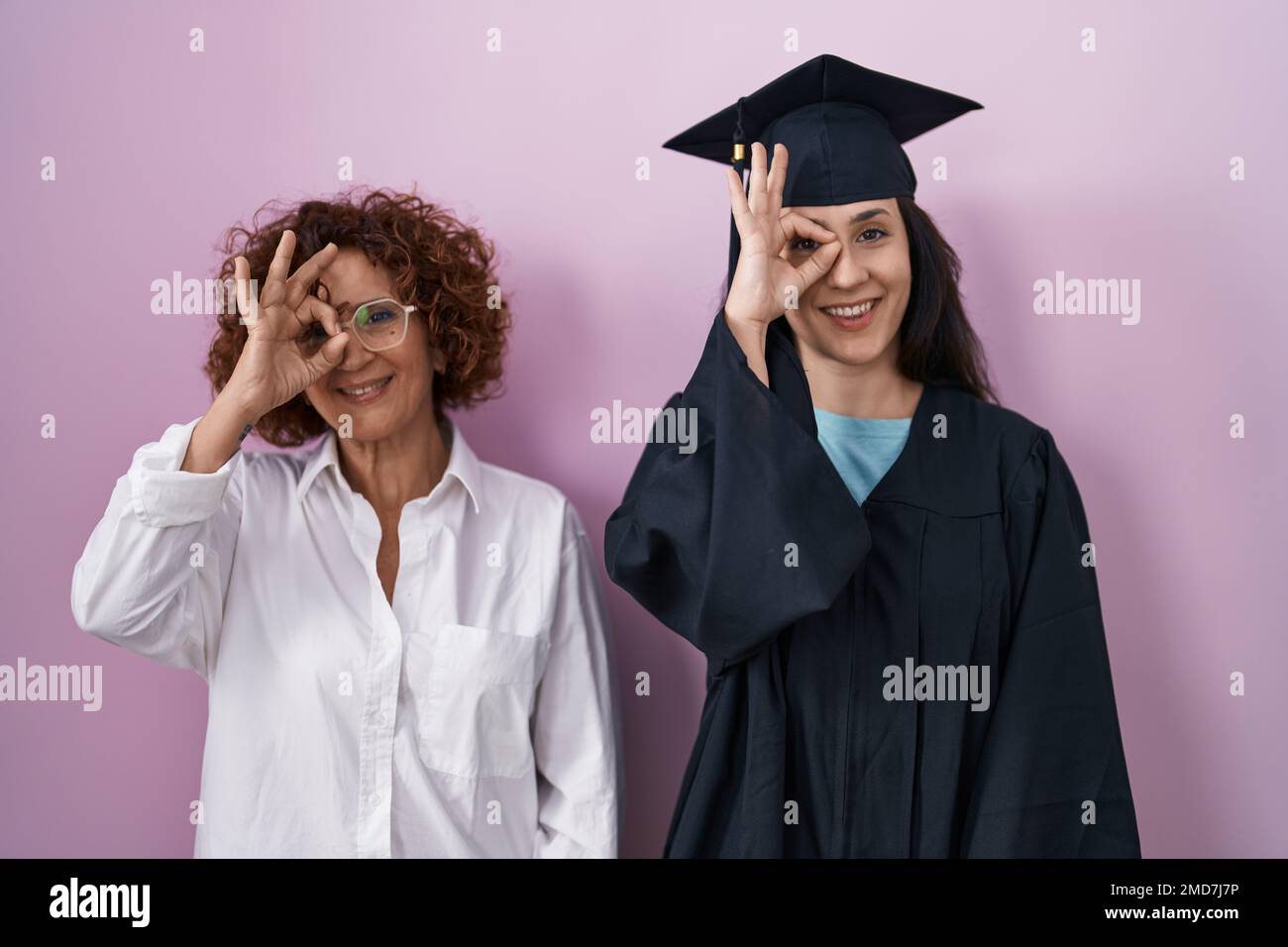 Hispanic mother and daughter wearing graduation cap and ceremony robe ...
