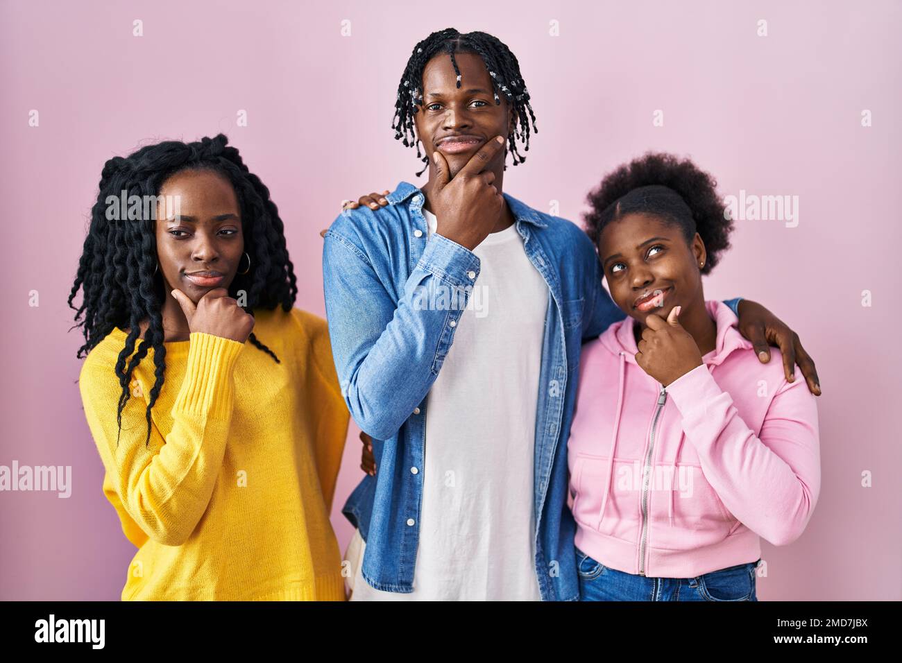 Group of three young black people standing together over pink ...