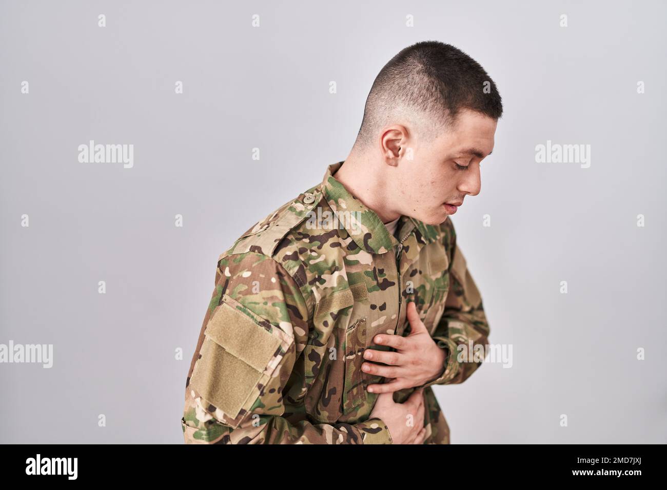 Young man wearing camouflage army uniform with hand on stomach because ...
