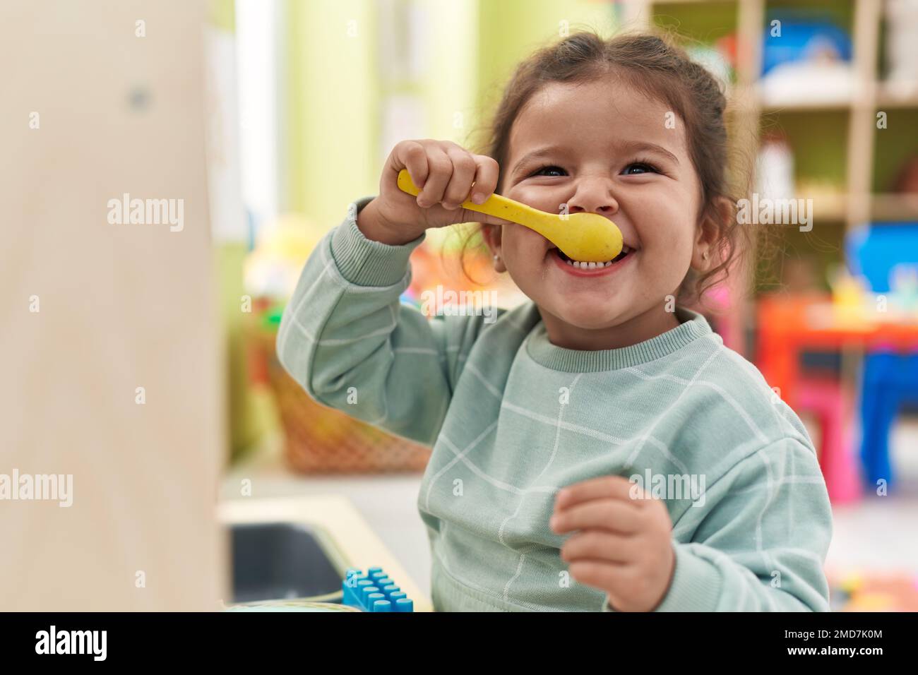 Adorable hispanic toddler playing with play kitchen standing at ...