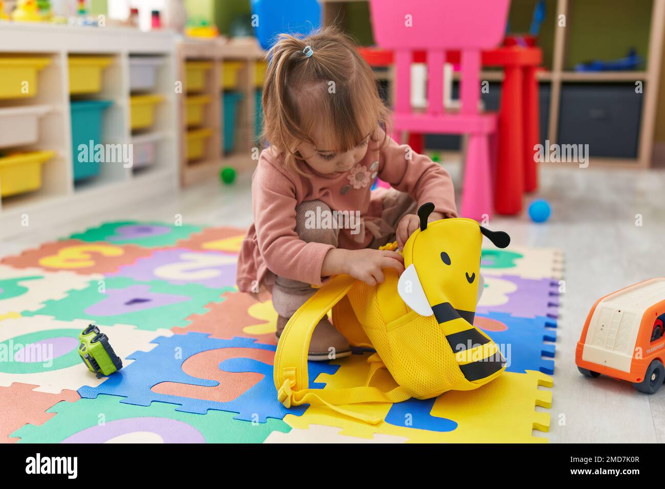 Adorable blonde girl preschool student opening backpack at kindergarten ...