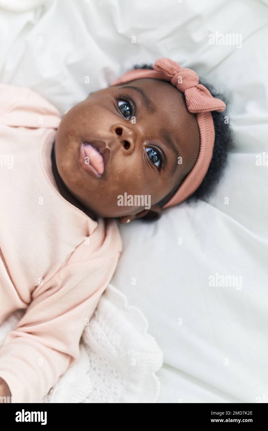 African american baby lying on bed with relaxed expression at bedroom ...