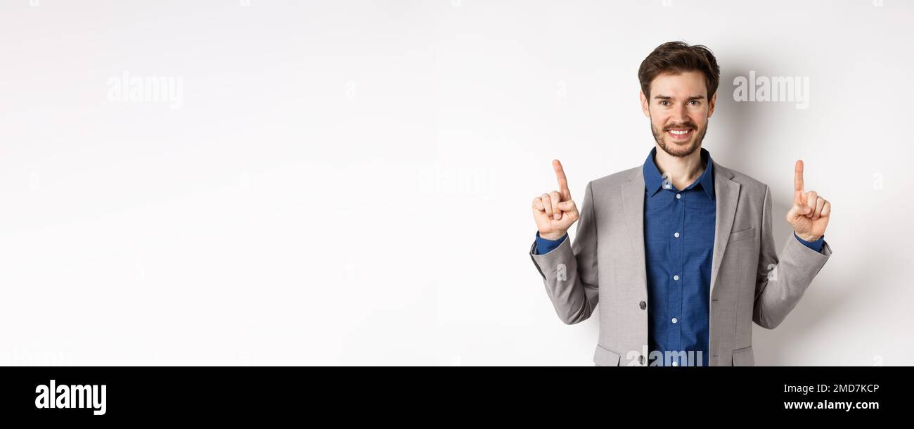 Confident successful businessman pointing fingers up, smiling and ...