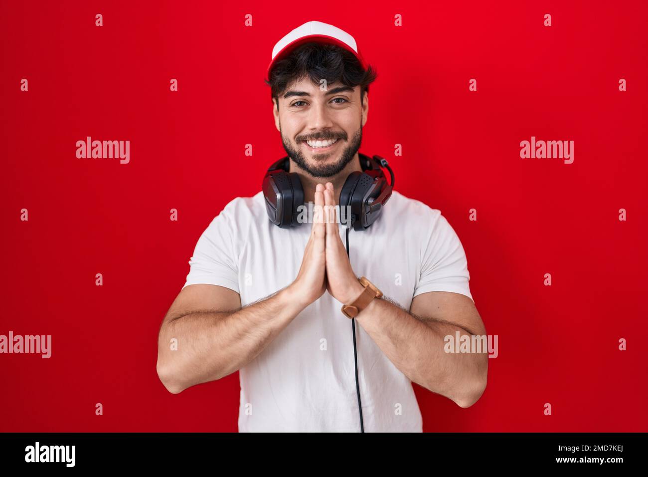 Hispanic man with beard wearing gamer hat and headphones praying with ...