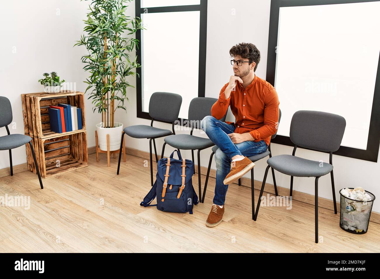 Young hispanic man boring sitting on chair at waiting room Stock Photo ...