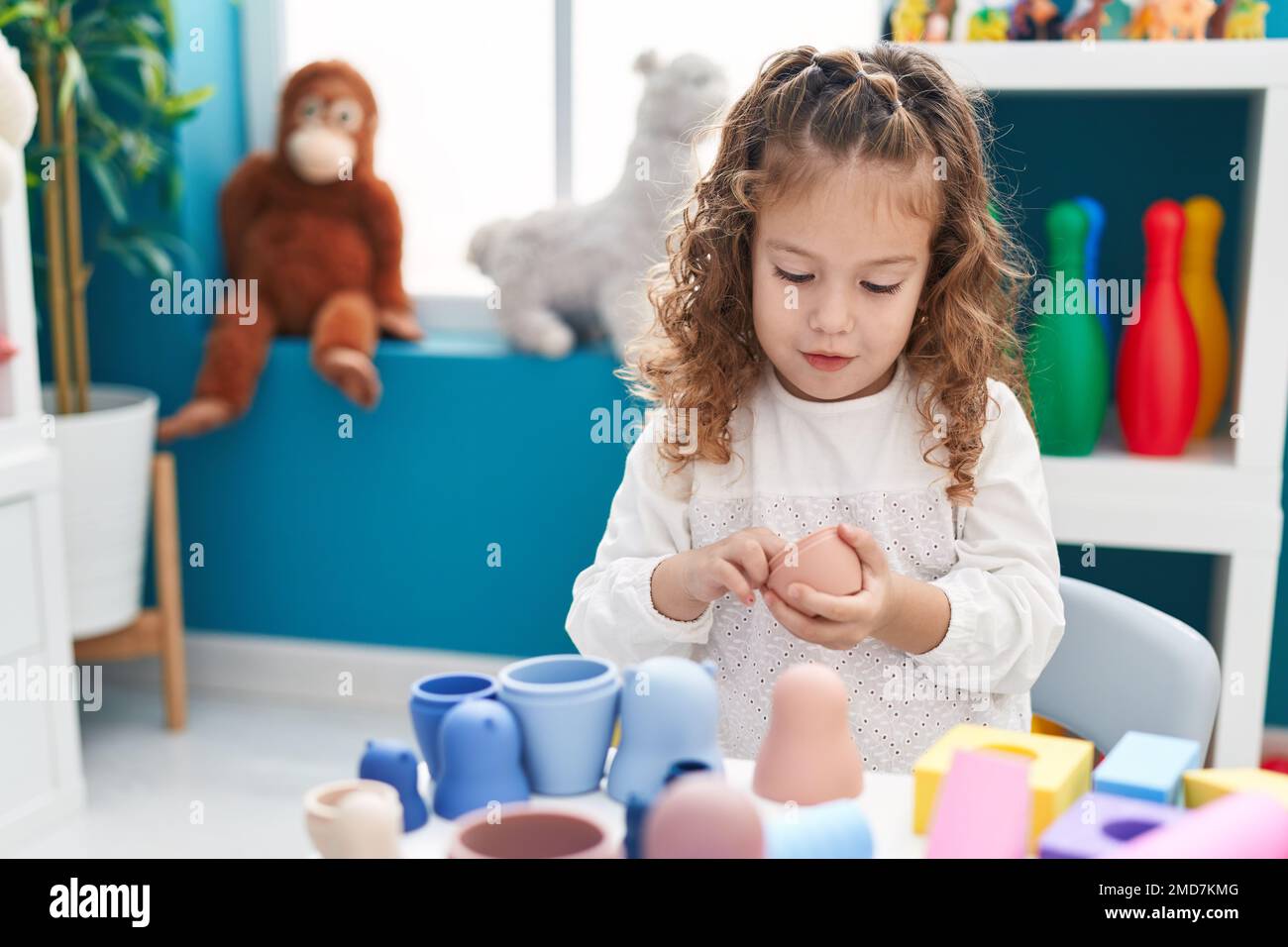 Adorable blonde toddler playing with toys standing at kindergarten ...