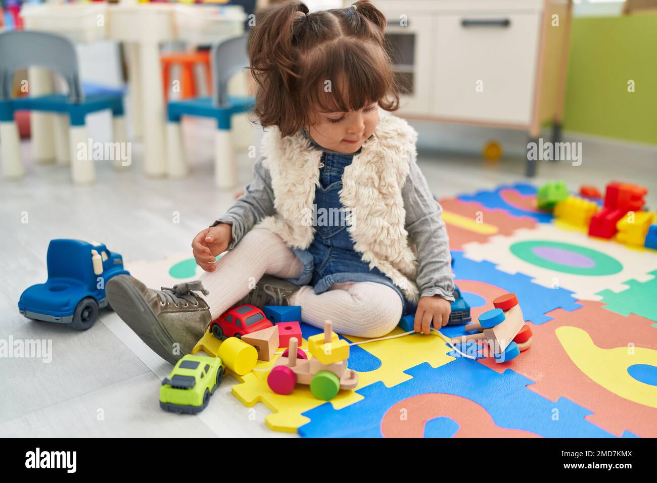 Adorable hispanic toddler playing with car toy sitting on floor at ...