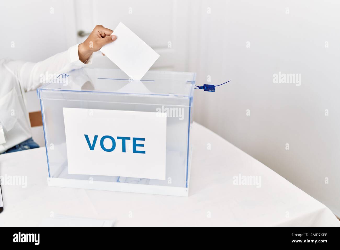 Young african american woman putting vote in box at electoral college ...