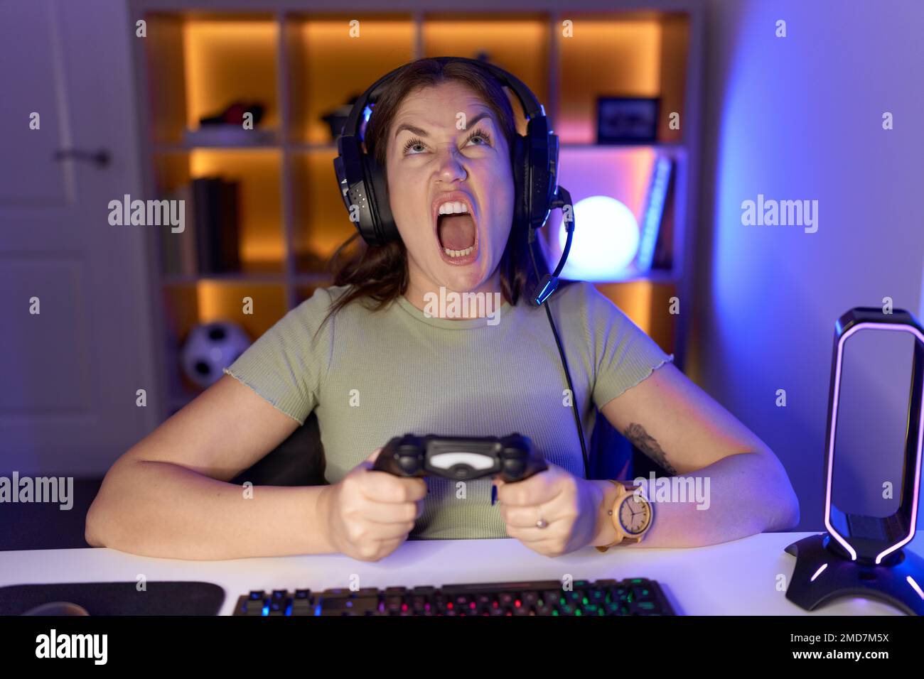 Beautiful brunette woman playing video games wearing headphones angry ...