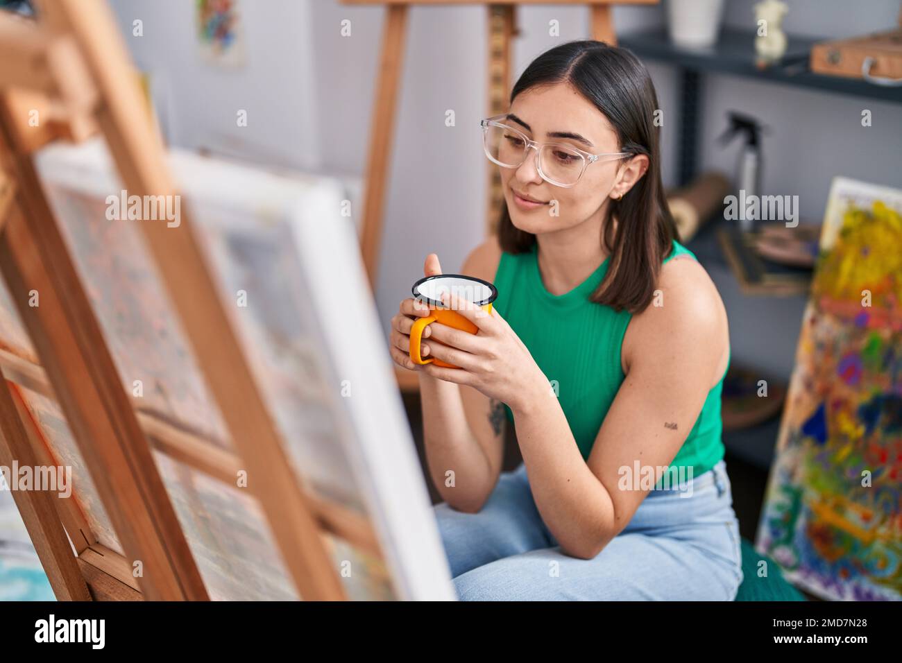 Young hispanic woman artist drinking coffee at art studio Stock Photo ...