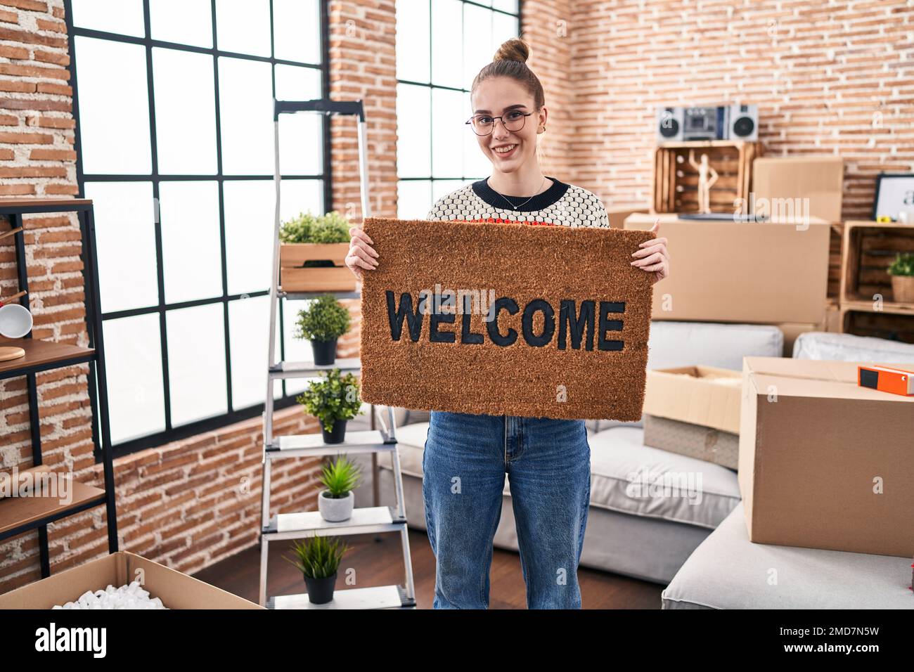 Young hispanic girl holding welcome doormat smiling with a happy and ...